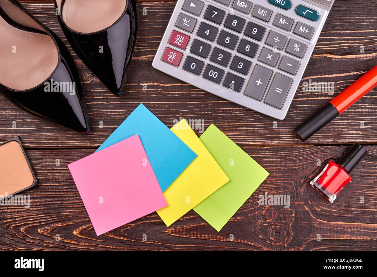 Black shoes with calculator and colored sticky notes. Brown wooden desk ...