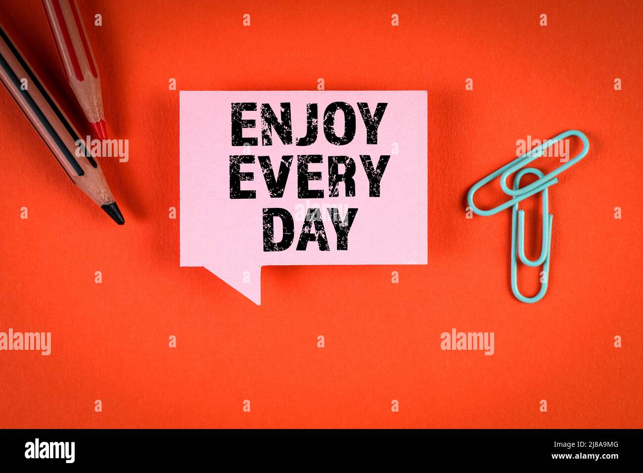 ENJOY EVERY DAY. Speech bubble and office supplies on an orange ...