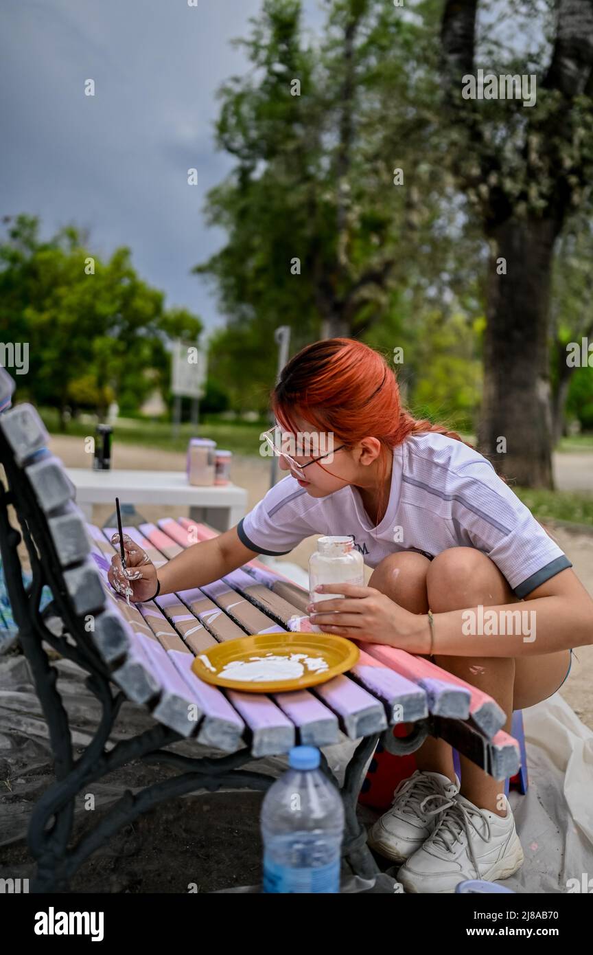 Local young illustrator Carla Loza paints a wooden bench at popular ...