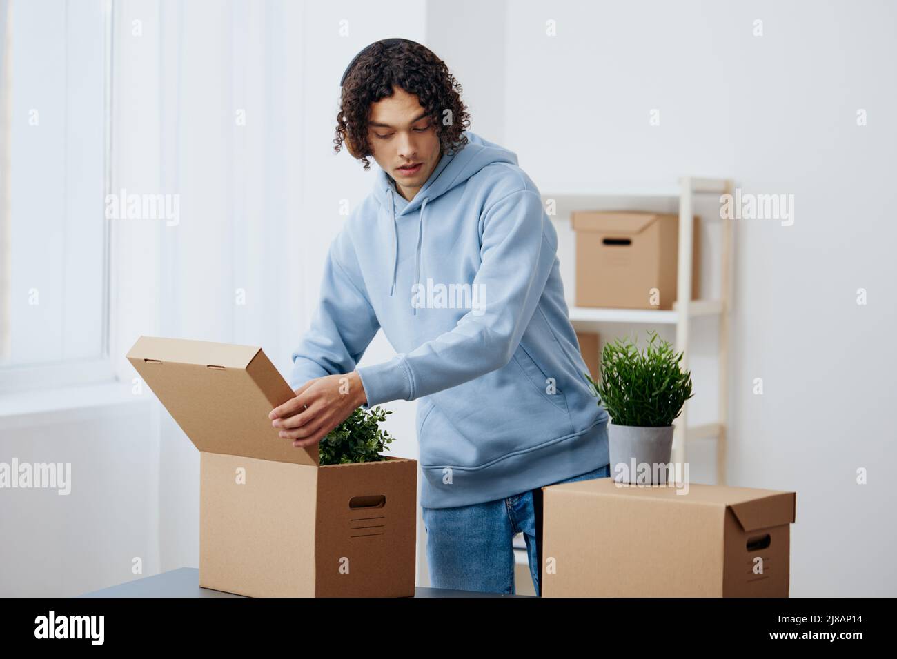guy with curly hair unpacking things from boxes in the room sorting ...