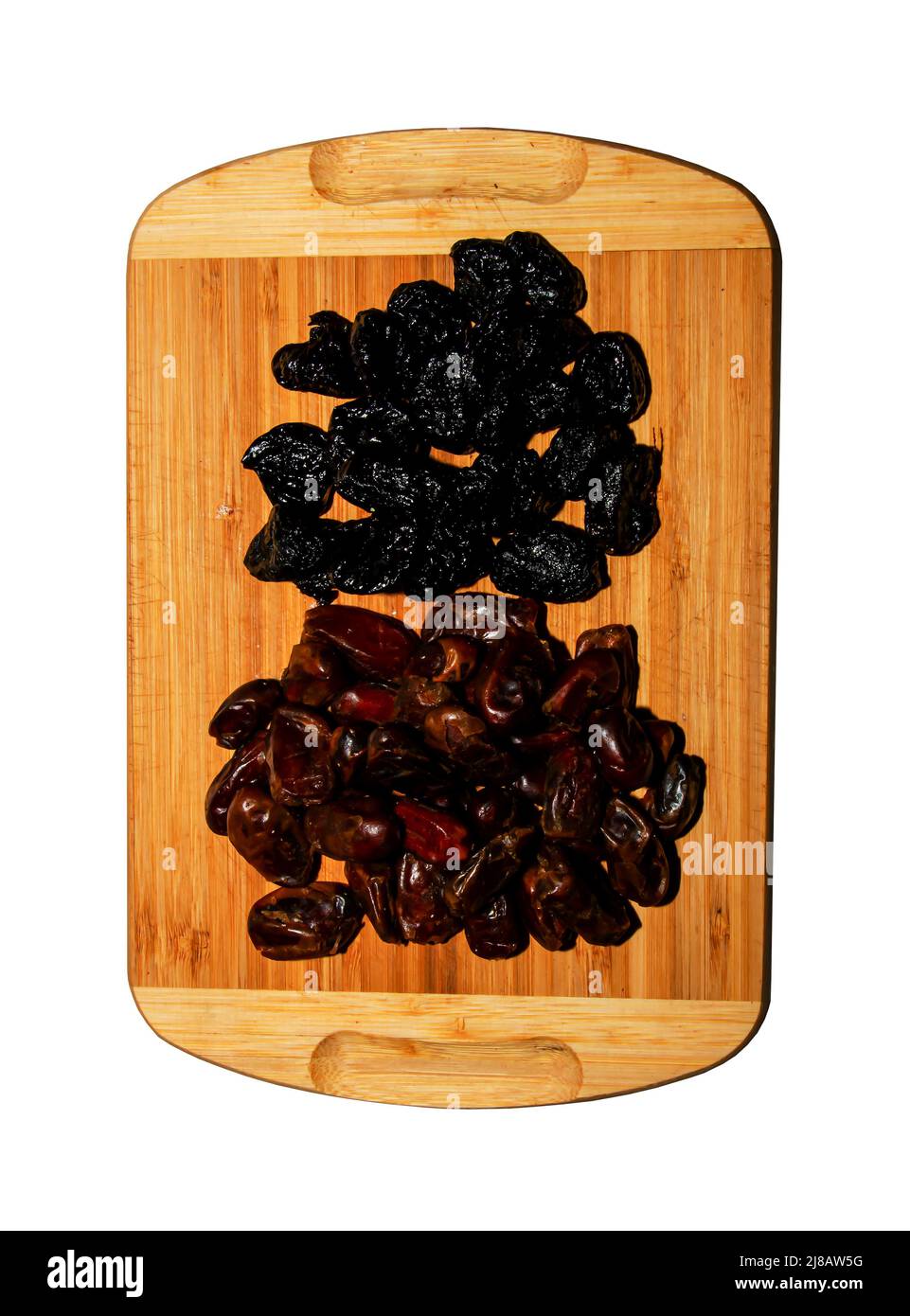 A handful of dried dates and prunes on a wooden kitchen board ...