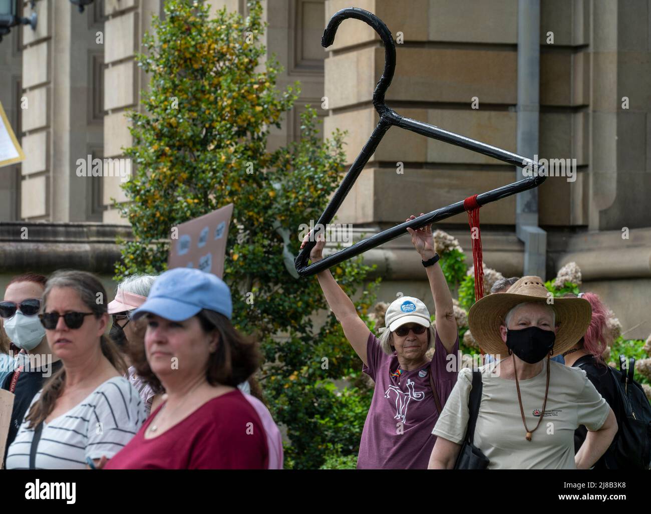 A woman holds up a giant coat hanger while demonstrating for women's ...