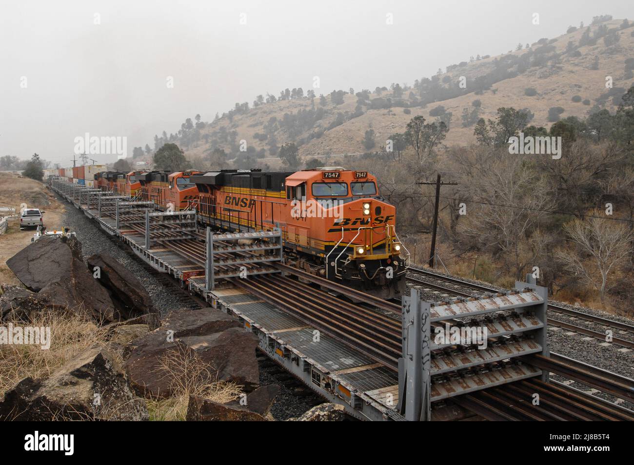 BNSF 7547 heads up a stack train moving uphill towards the Tehachapi loop as it passes rail cars ...
