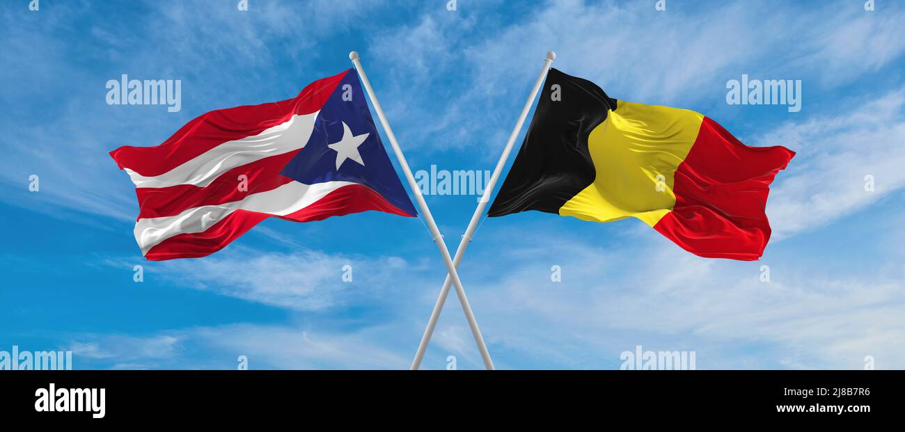 two crossed flags Puerto Rico and Belgium waving in wind at cloudy sky. Concept of relationship ...
