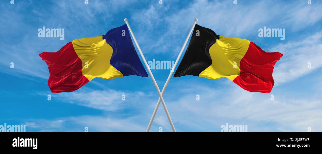 two crossed flags romania and Belgium waving in wind at cloudy sky ...