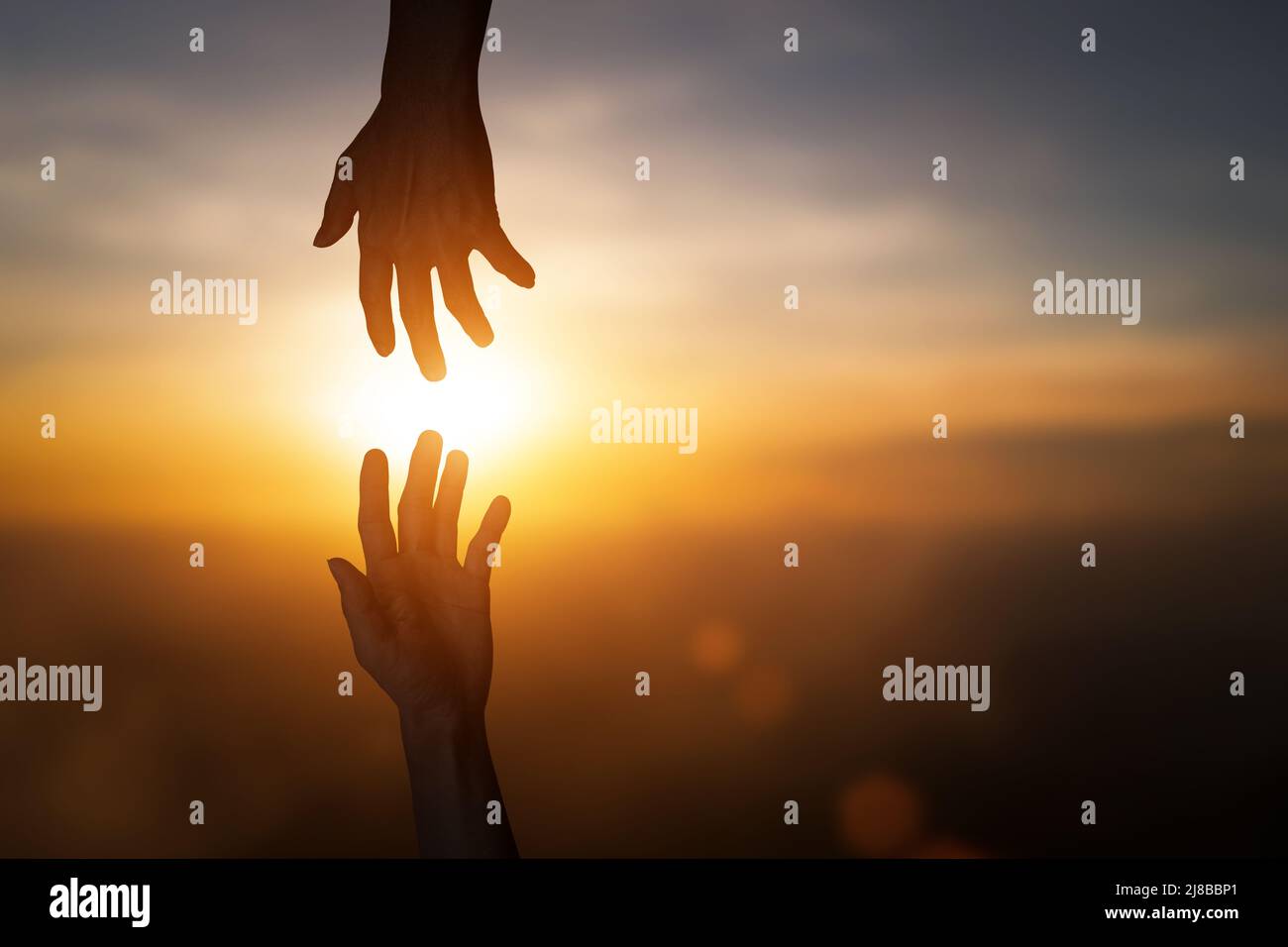 Silhouette of reaching, giving a helping hand, hope and support each other over blur sunset sky ...