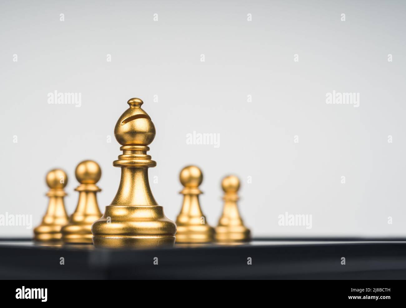The golden bishop chess piece in front gold pawns on white background ...