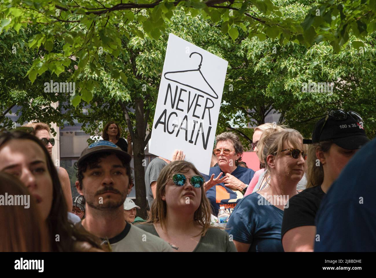 A protester displays a symbolic coat hanger placard that says "Never ...