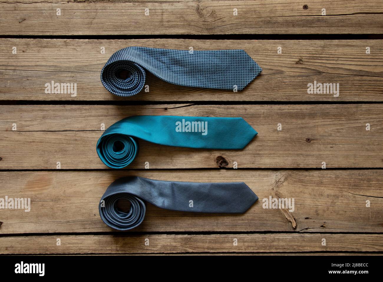 Three blue ties lie on a wooden table, different men's ties close-up ...
