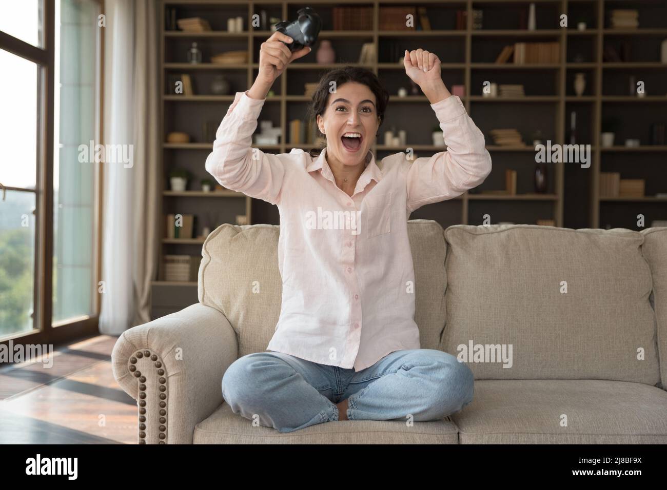 Overjoyed young woman celebrate video game victory Stock Photo - Alamy
