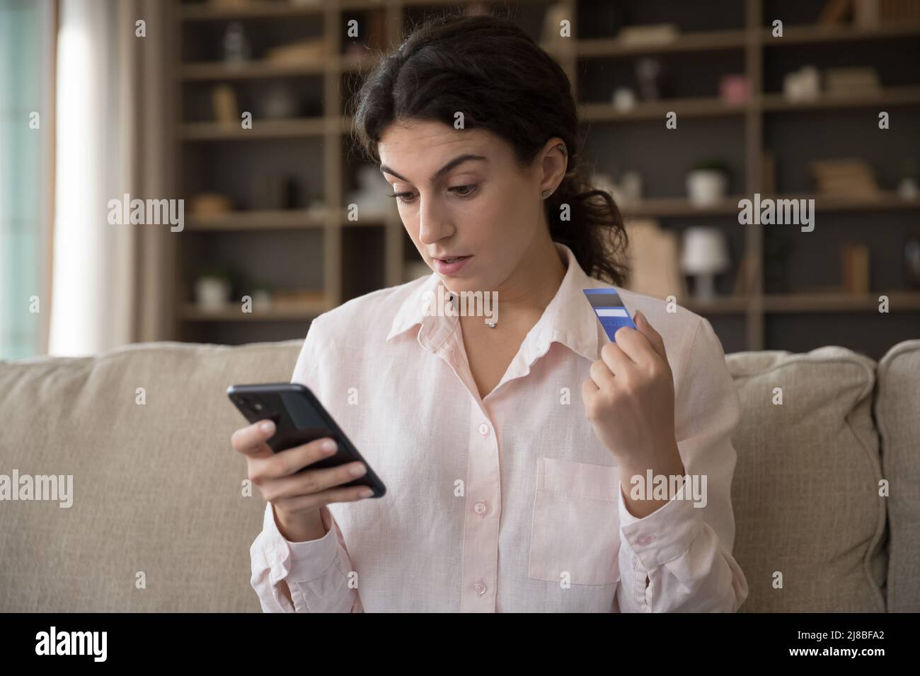 Woman holds debit card staring at smartphone screen Stock Photo - Alamy