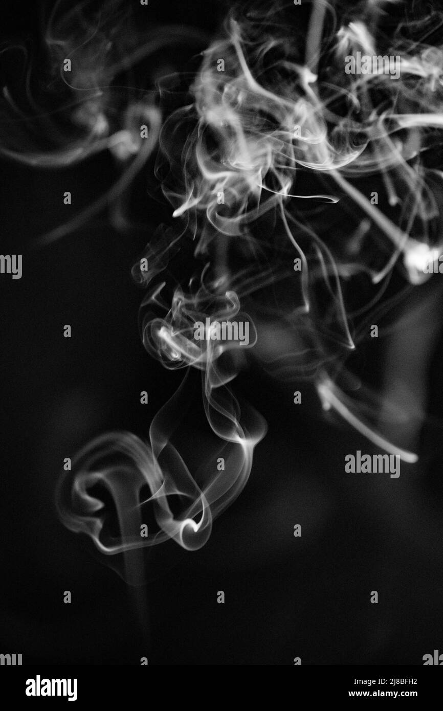 Black and white swirling, ascending smoke pattern on a black background ...