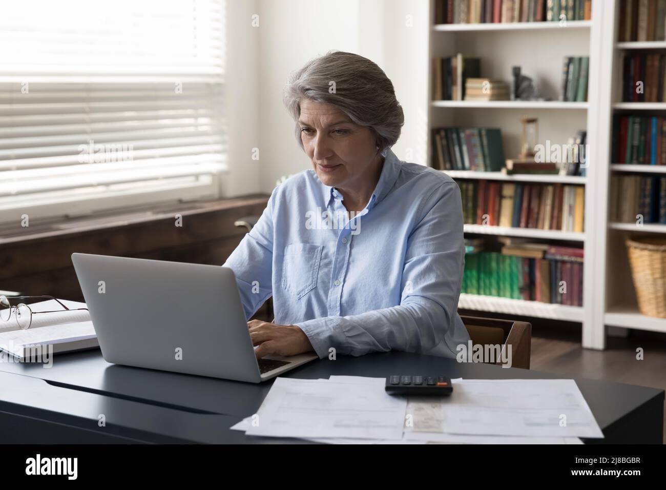 Focused positive elder business woman, accountant counting annual ...