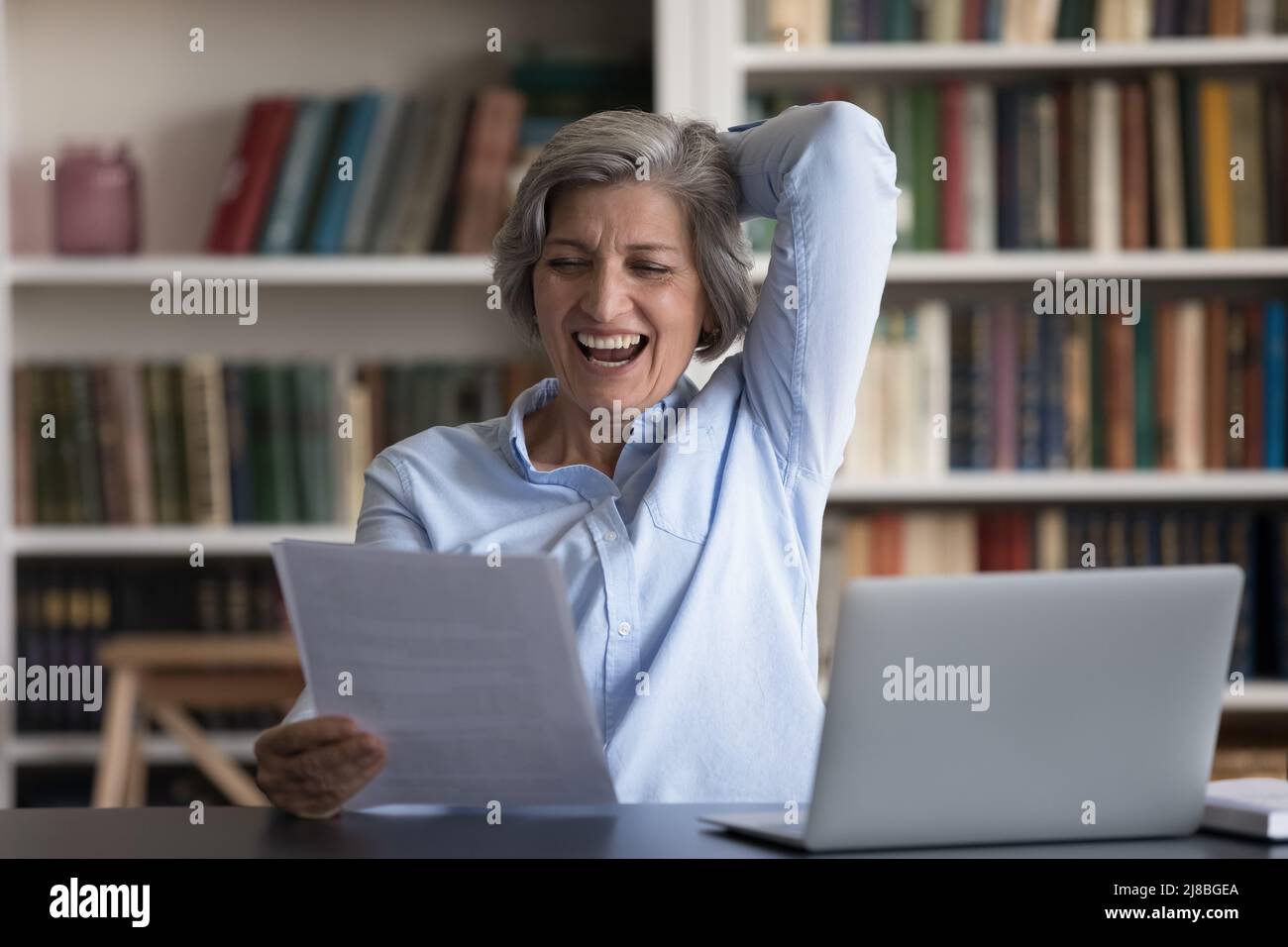 Excited business lady reading document at workplace with laptop Stock ...