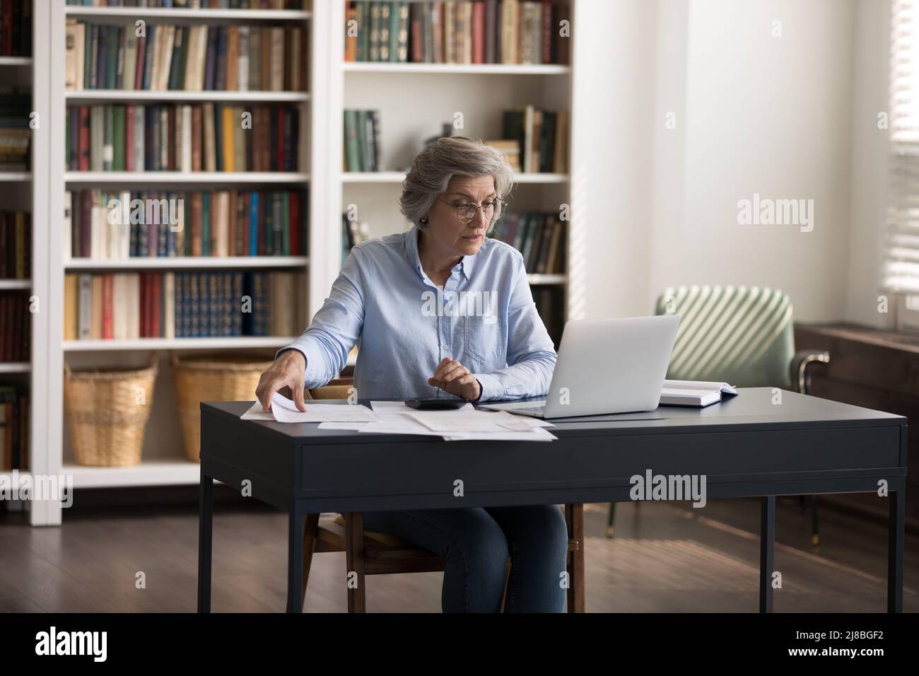 Serious mature business lady doing financial accounting paperwork Stock ...