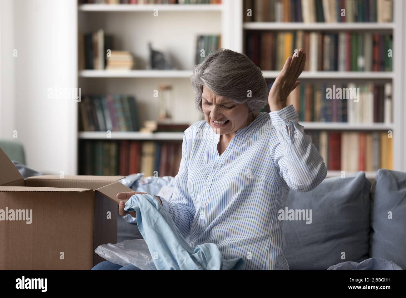 Angry frustrated senior customer woman receiving parcel with damaged ...