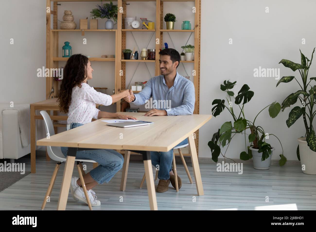 Happy coworkers shaking hands over table due to completing project ...