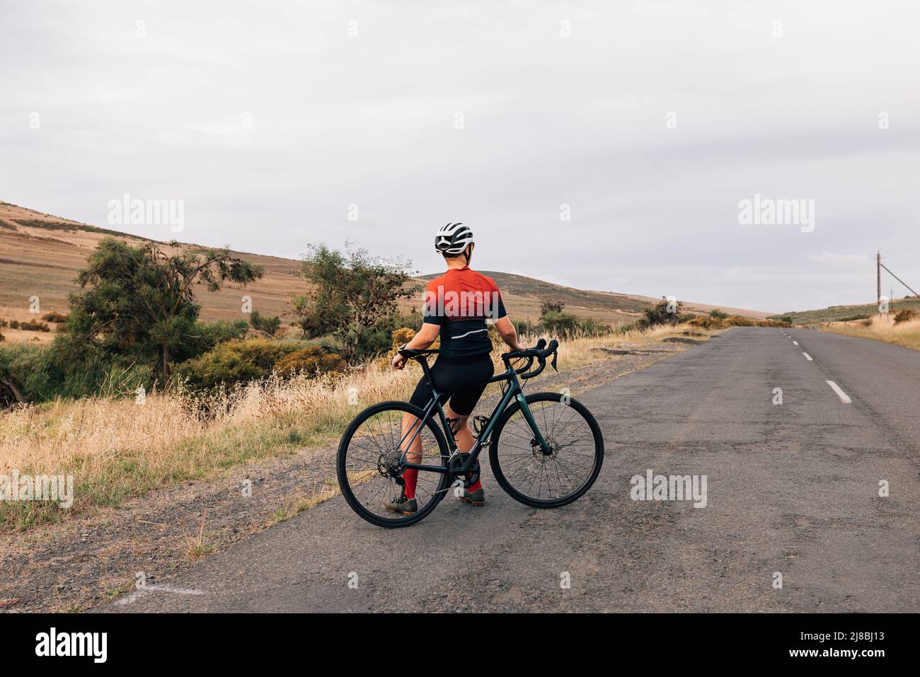 Rear view of professional woman cyclist sitting on her road bike ...
