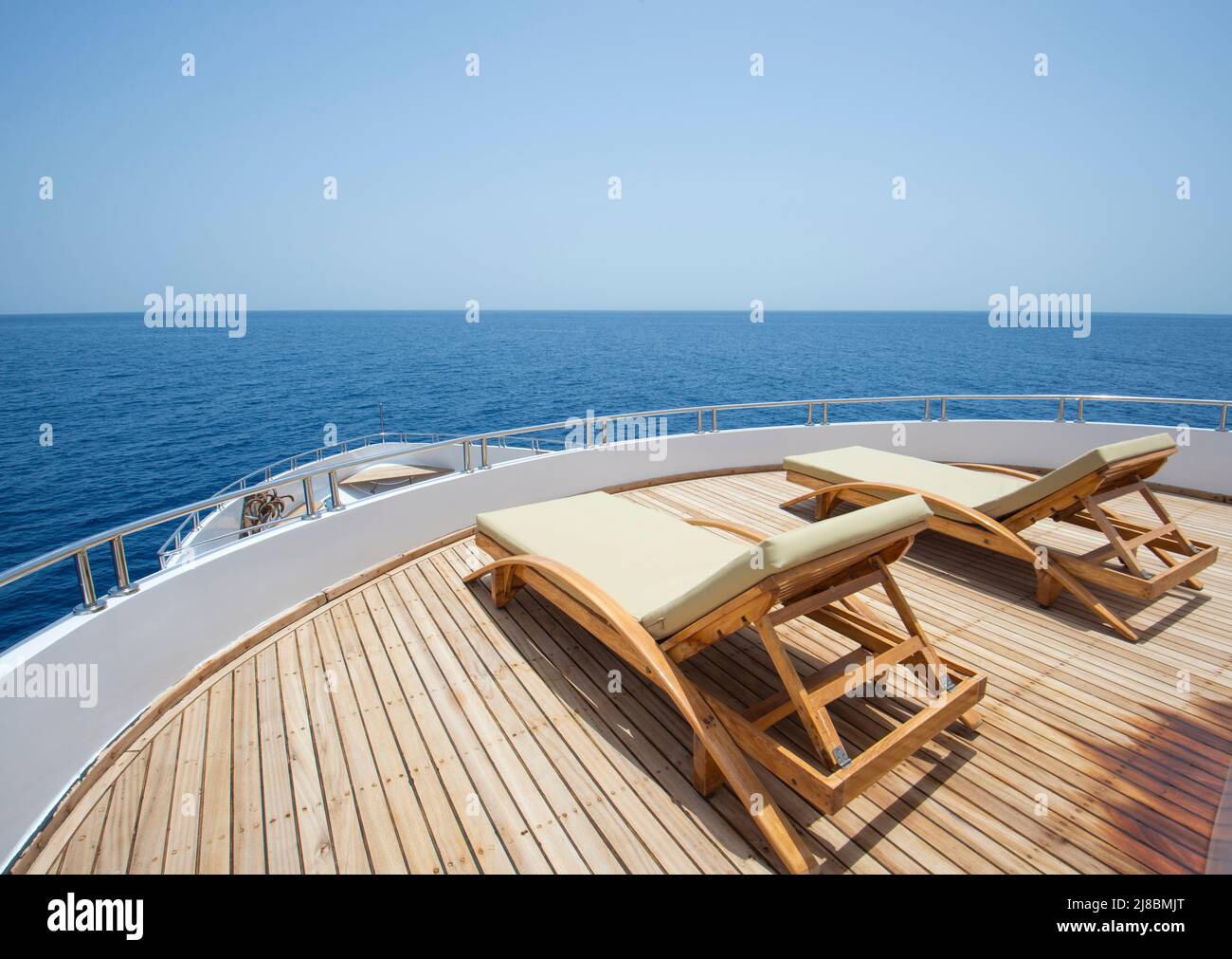 Teak bow sundeck of a large luxury motor yacht out at sea with sunbeds ...