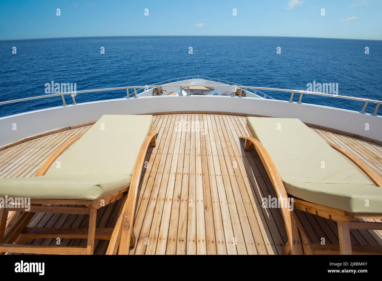 Teak bow sundeck of a large luxury motor yacht out at sea with sunbeds ...