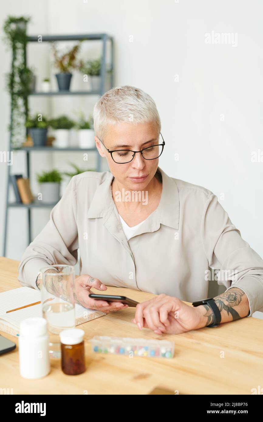 Serious Middle Aged Businesswoman In Eyeglasses Checking Time On Watch