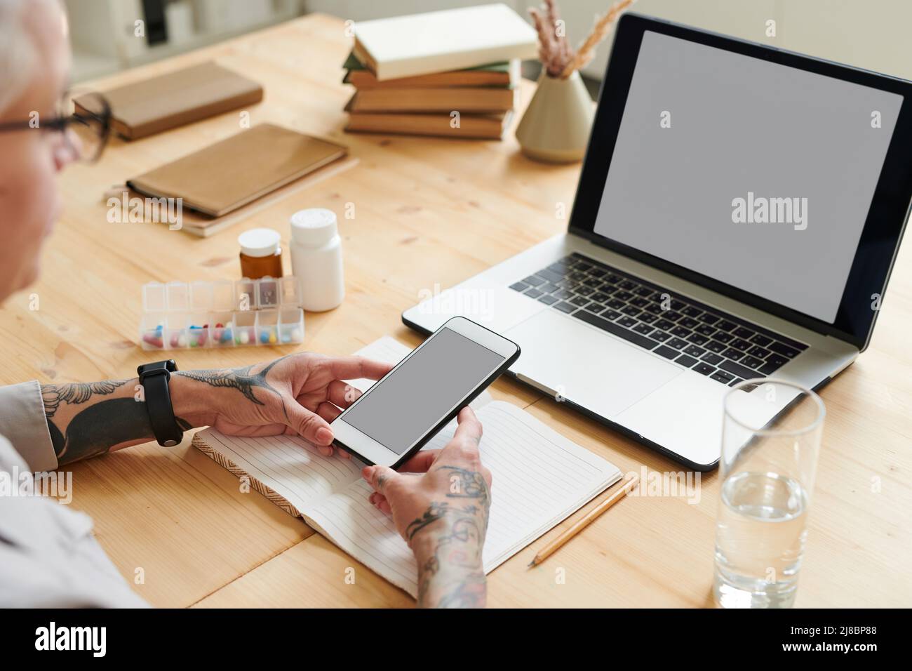 Over shoulder view of busy woman checking phone while synchronizing it ...