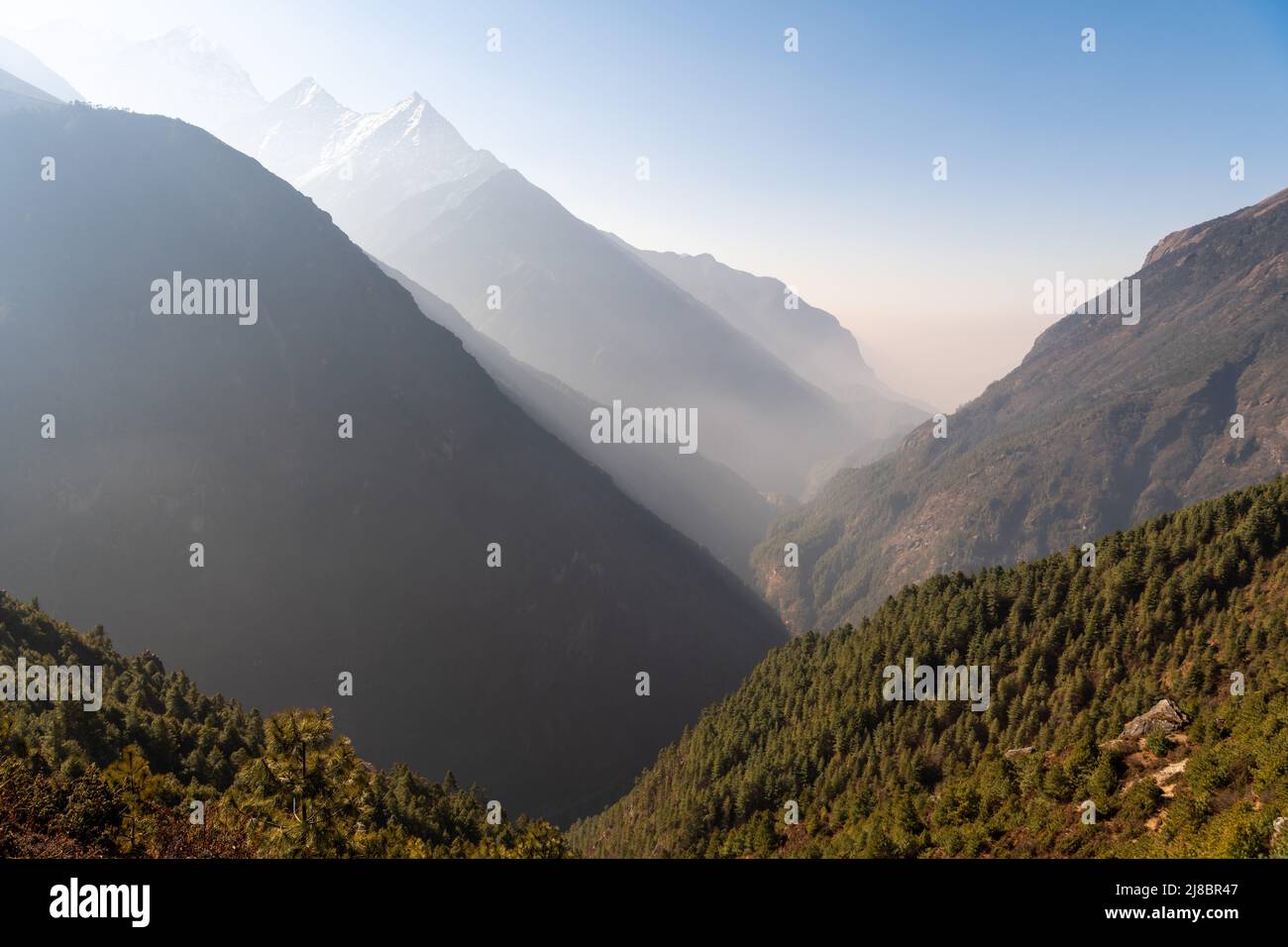 Nature in Nepal, high mountains with a trees in a shadow on a blue sky ...