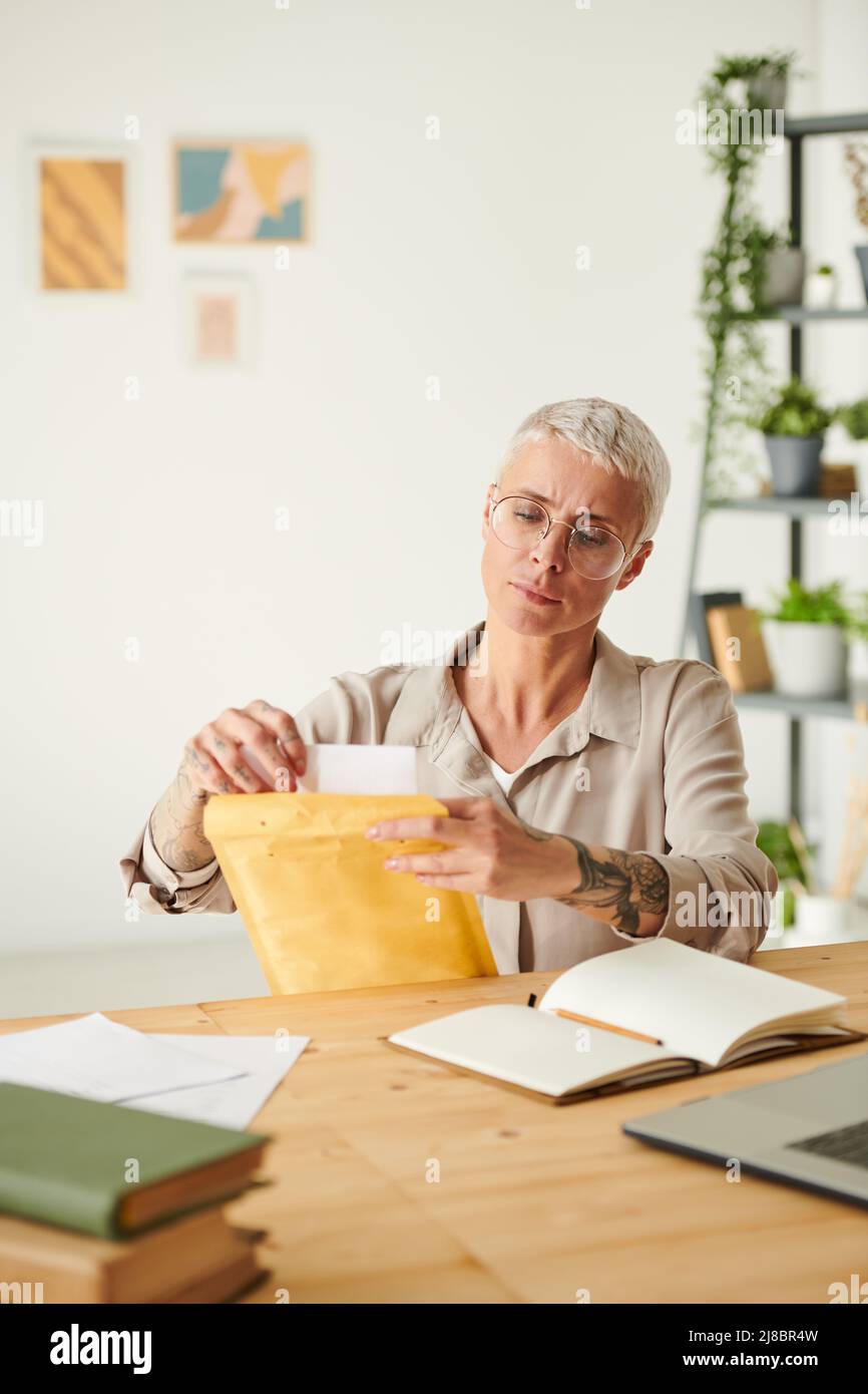 Attractive middle-aged businesswoman with short hair sitting at desk ...