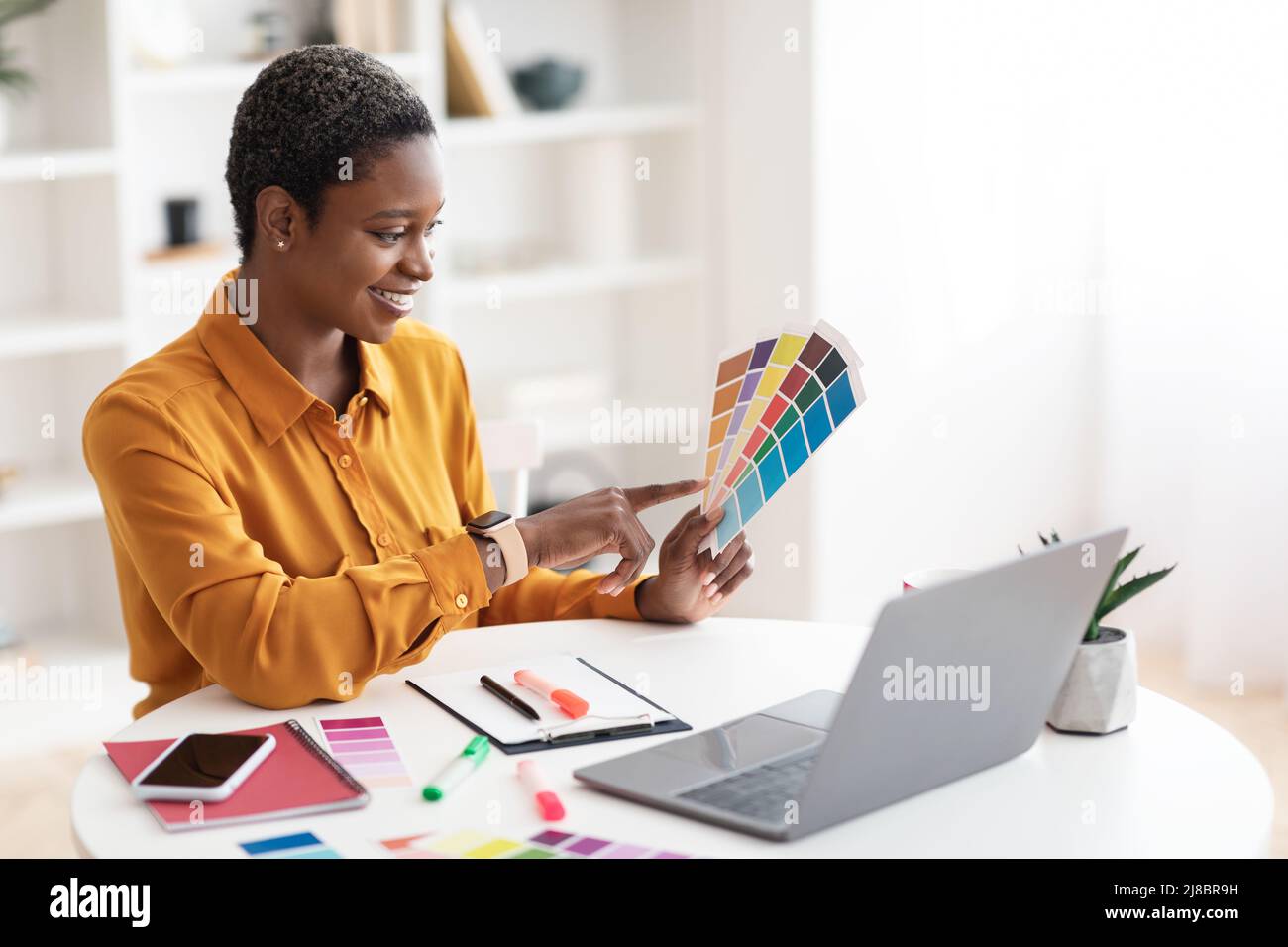 Smiling black woman working as web designer, office interior Stock ...