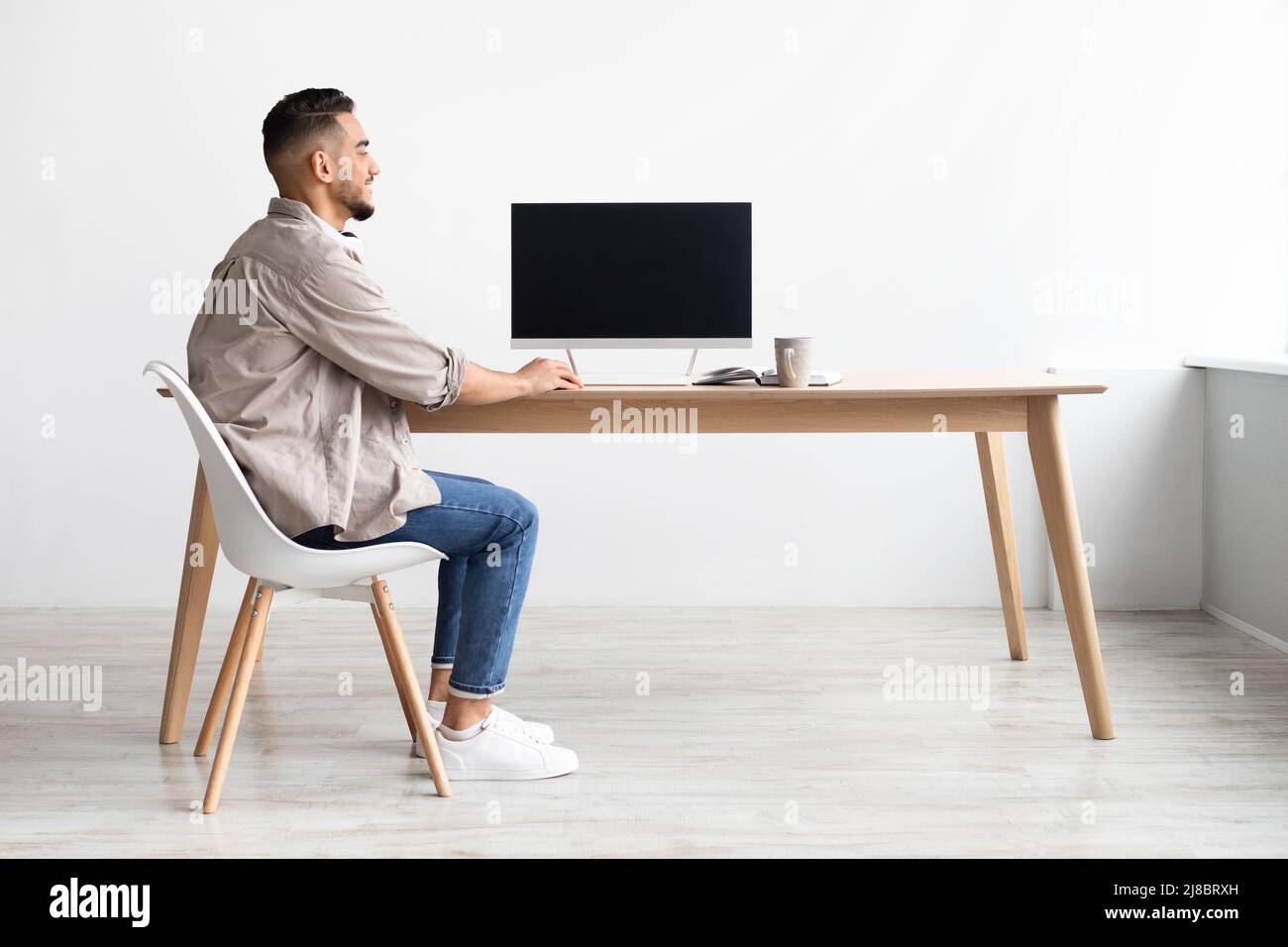Arab man using computer with blank empty monitor Stock Photo - Alamy