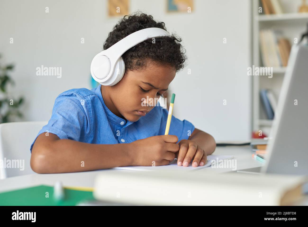 Concentrated black boy with curly hair listening to teacher advice and ...