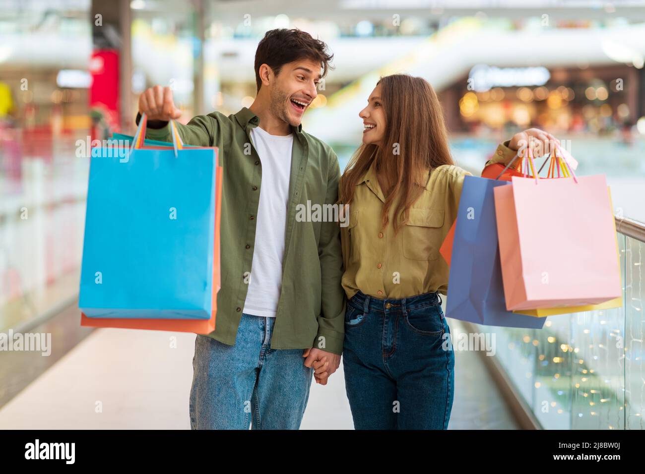 Excited Couple Showing Colorful Shopper Bags Shopping In Mall Stock ...