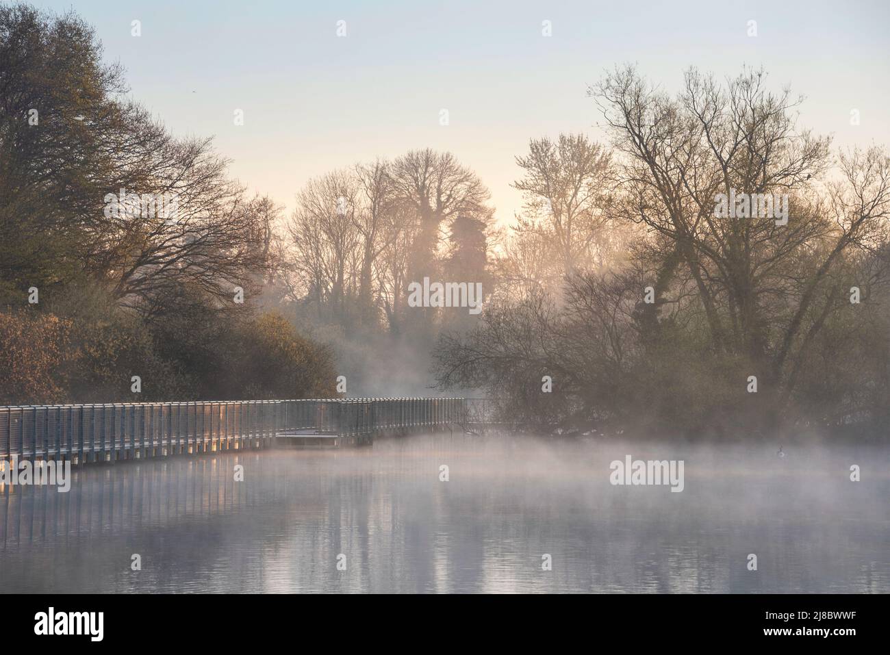 Stunning landscape image of sunrise mist on urban lake with sun beams ...