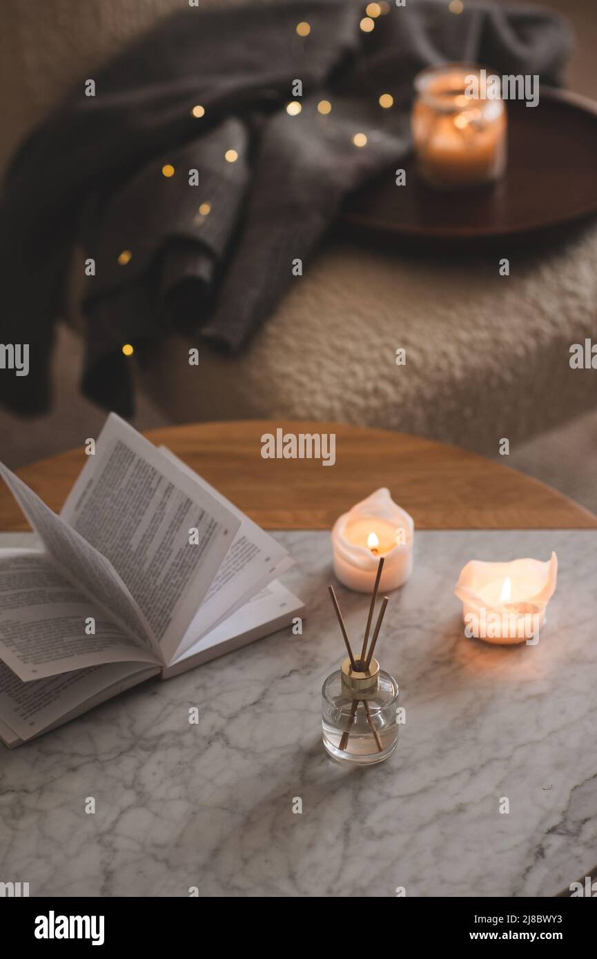 Liquid home fragrance in diffuser with open paper book on coffee table ...