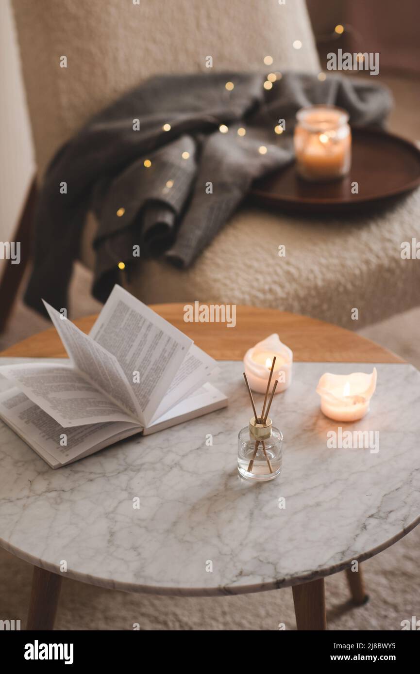 Liquid home fragrance in diffuser with open paper book on coffee table ...