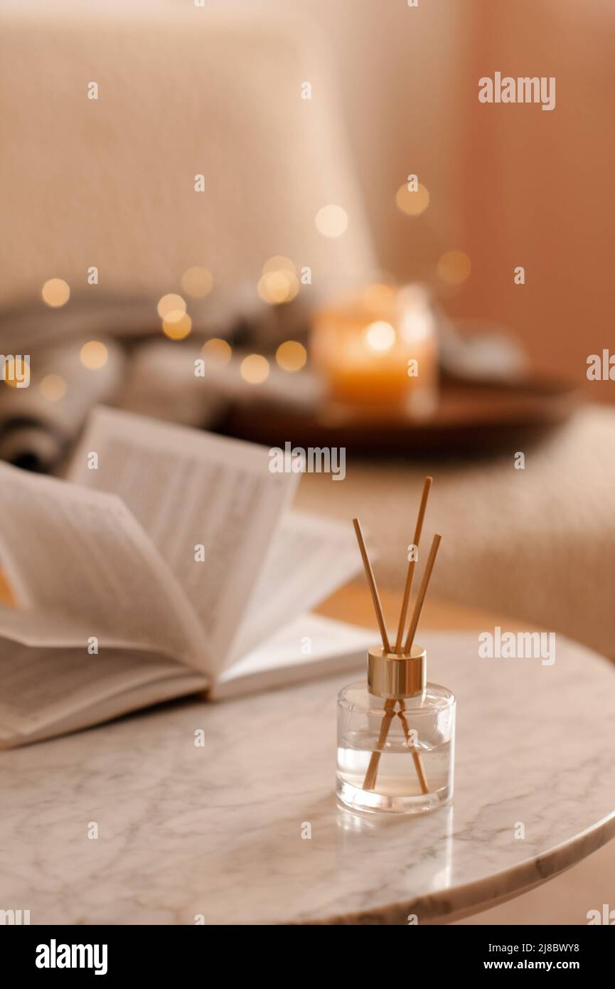 Liquid home fragrance in diffuser with open paper book on coffee table ...