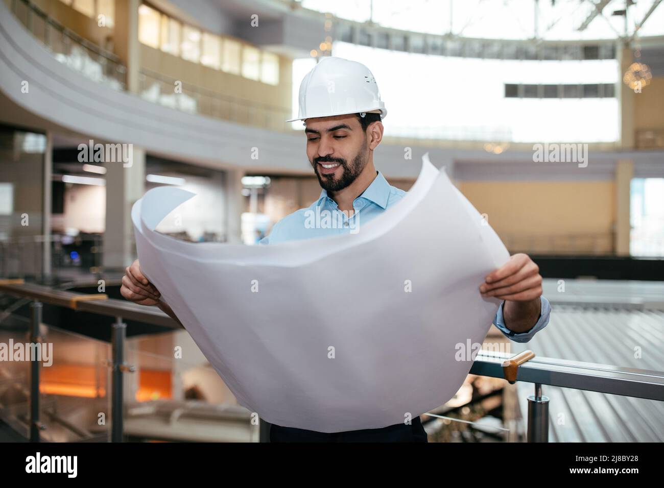 Happy attractive millennial muslim guy engineer with beard in hardhat ...