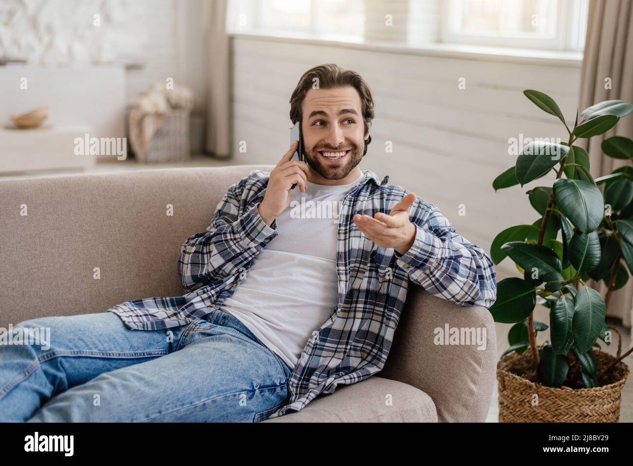 Glad Attractive Millennial Caucasian Guy With Stubble Speaks On Phone
