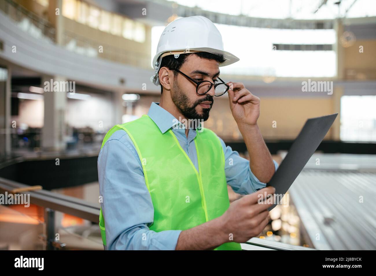 Serious attractive young arab guy engineer with beard in helmet ...