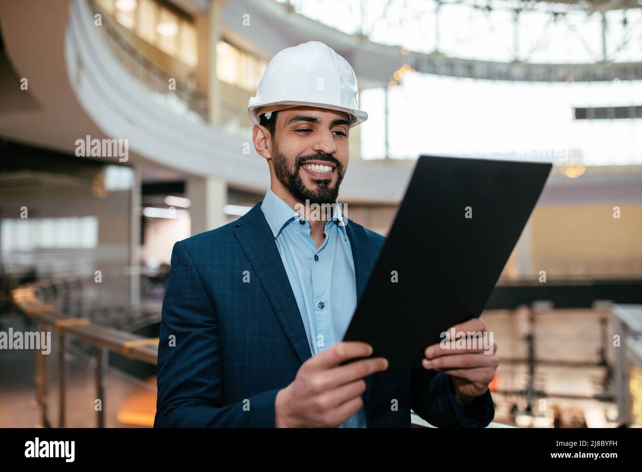 Smiling handsome young arab male engineer, architect or builder with ...