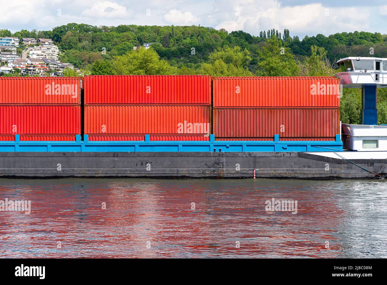 A barge carrying many containers on the Rhine in western Germany, trees ...