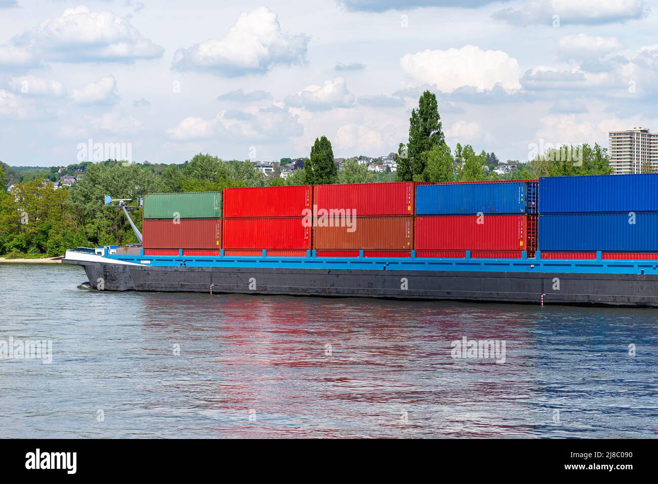 A barge carrying many containers on the Rhine in western Germany, trees ...