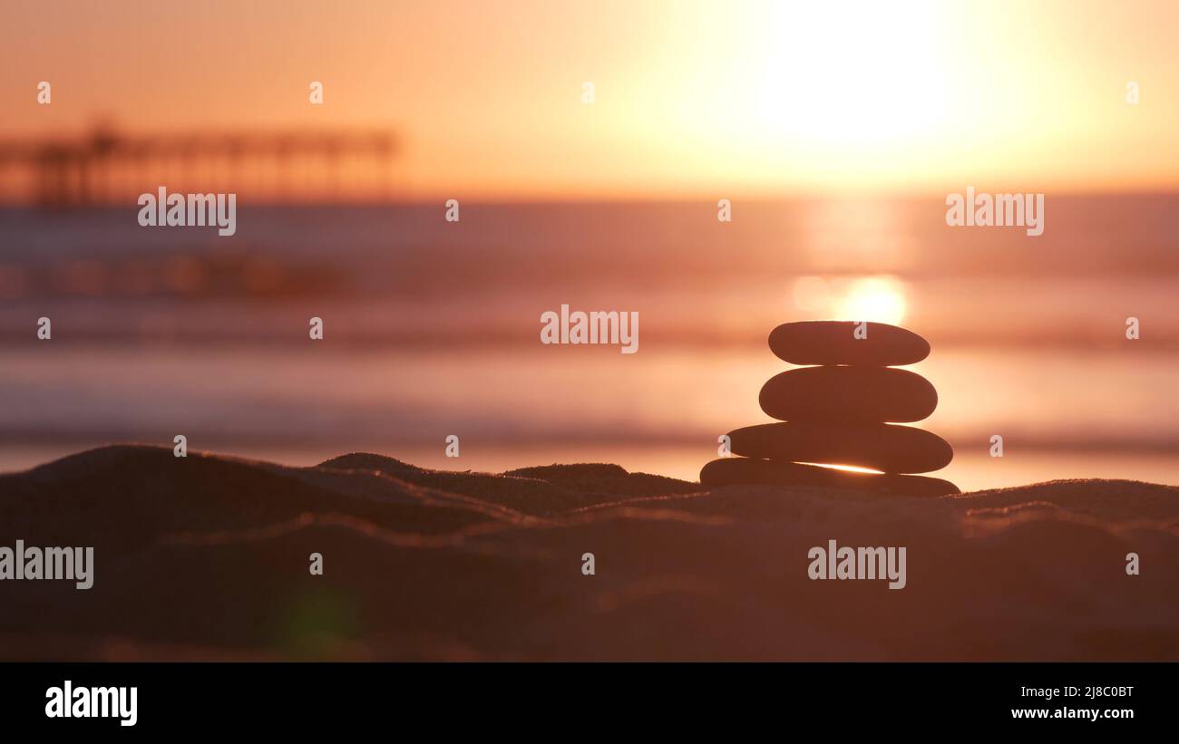 Stack of pebble stones, sandy ocean beach, sunset sky. Rock balancing ...