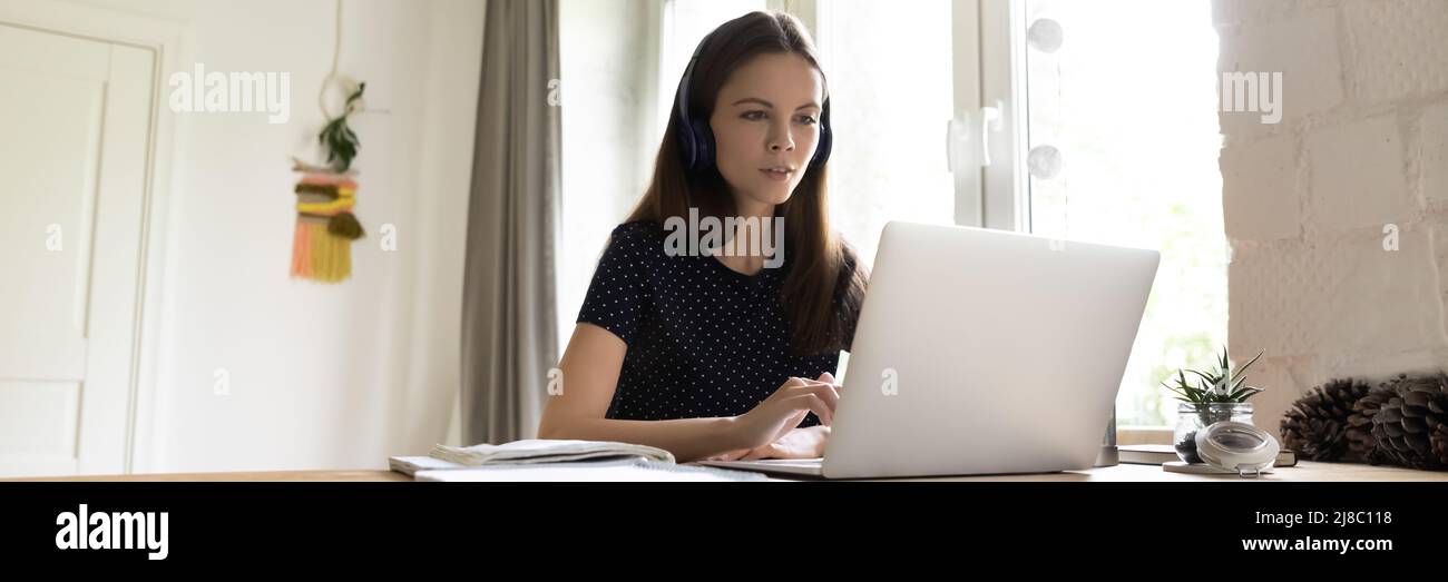 Focused student girl in wireless headphones watching learning video ...