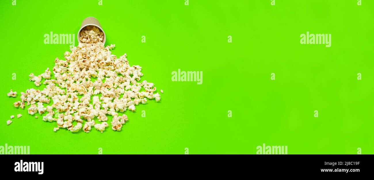 Popcorn spills out of a paper cup on a green background close-up Stock ...