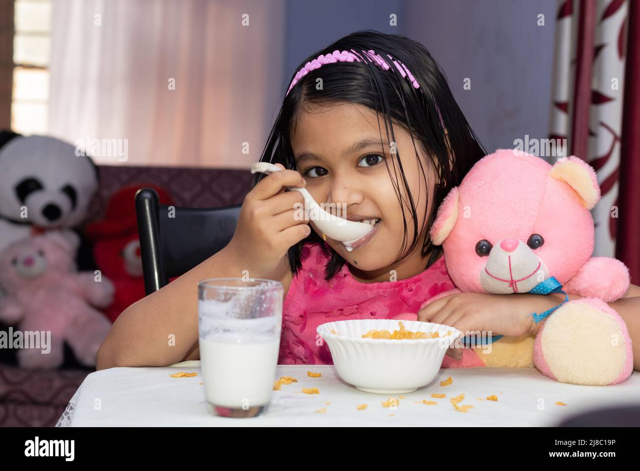 An Indian girl child eating cereal with milk with smiling face and ...
