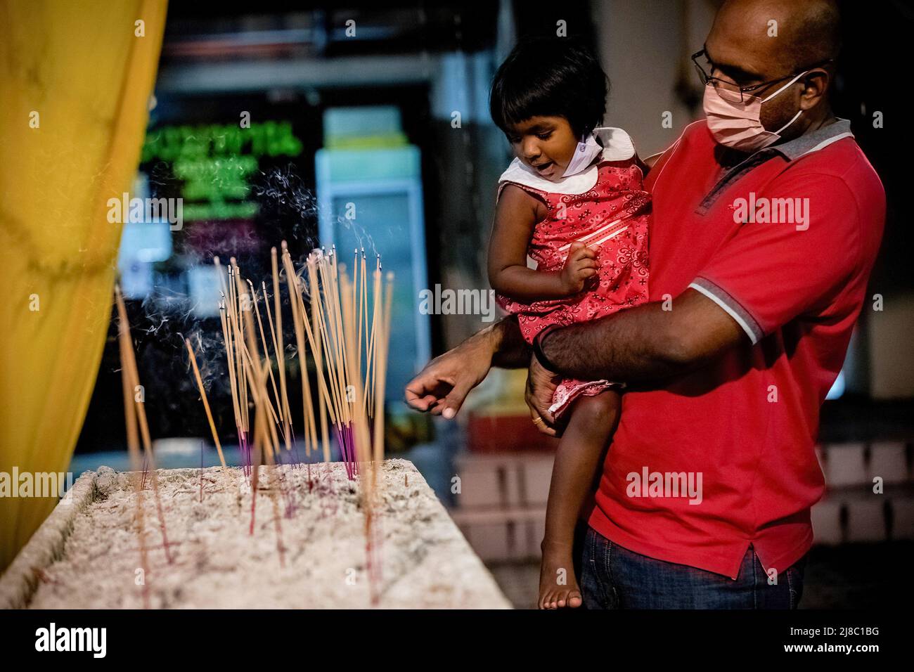 A Buddhist devotee carrying a child performs a religious ritual in ...
