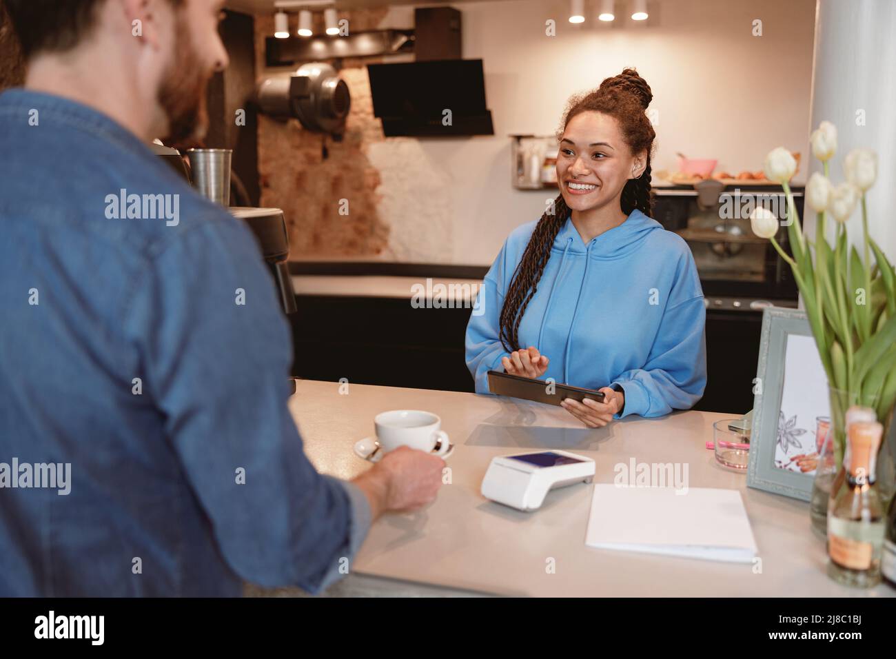 Back view on man client at cafeteria counter taking away cup of coffee ...