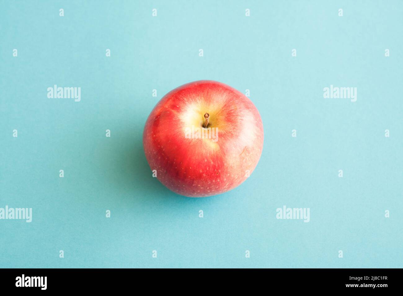 Minimalist image of a red apple on blue background Stock Photo - Alamy