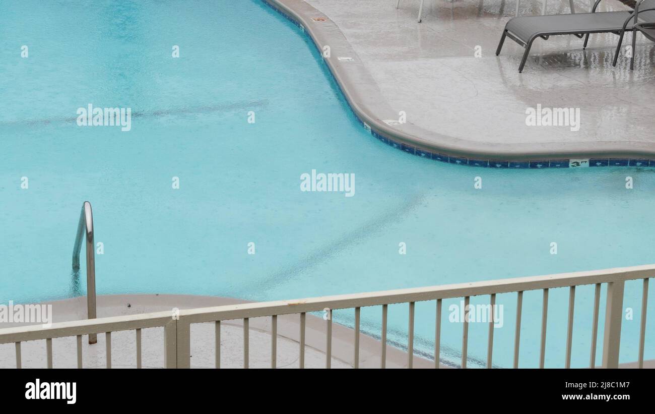 Rain drops falling on water surface of blue swimming pool, rainy day in ...